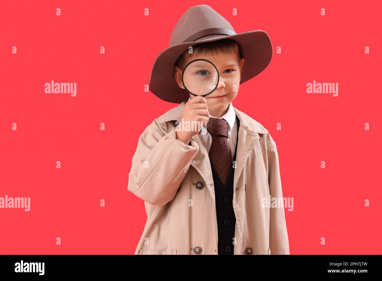 Cute little detective with magnifier on red background Stock Photo - Alamy