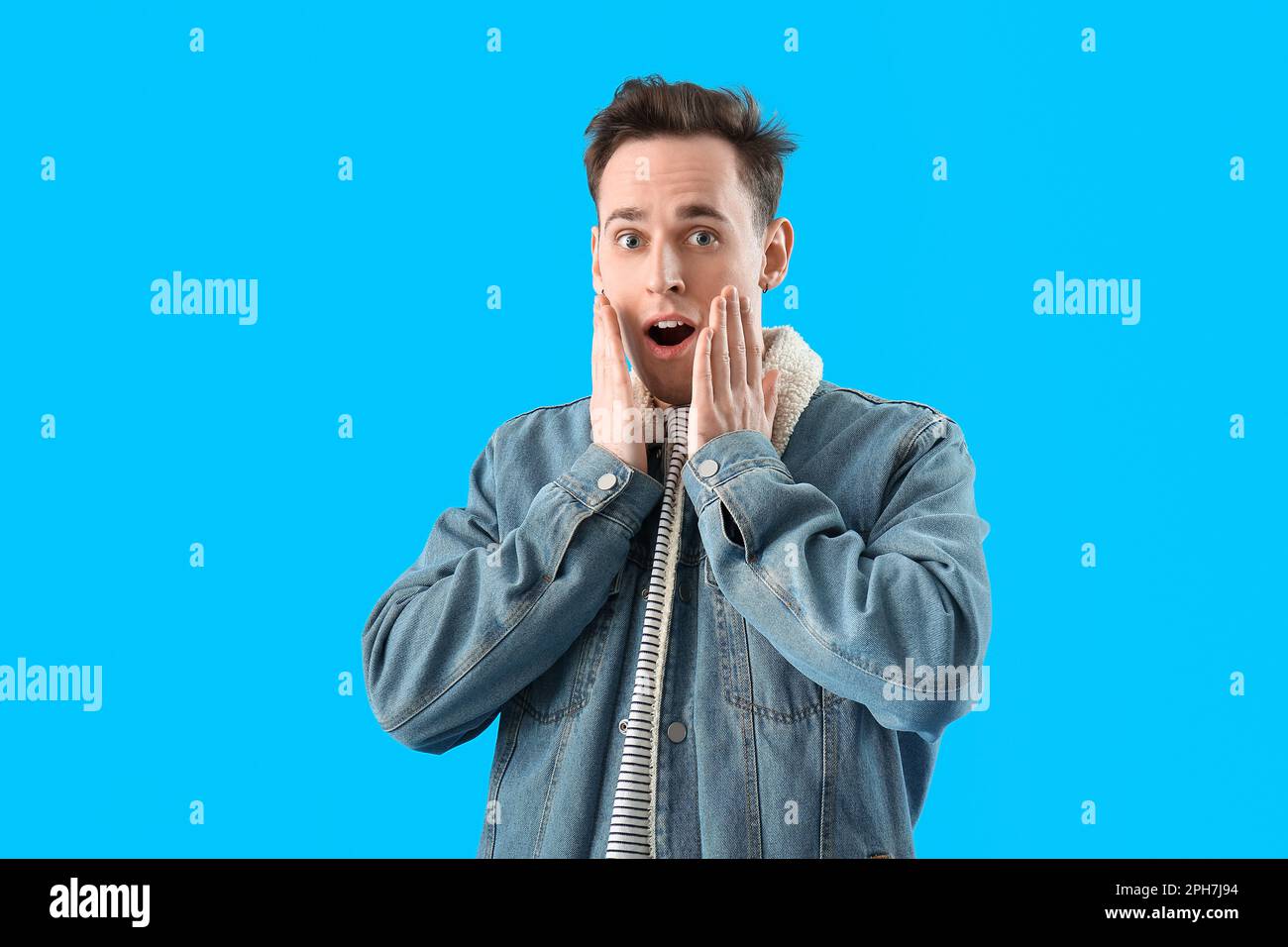 Scared young man on light blue background Stock Photo - Alamy
