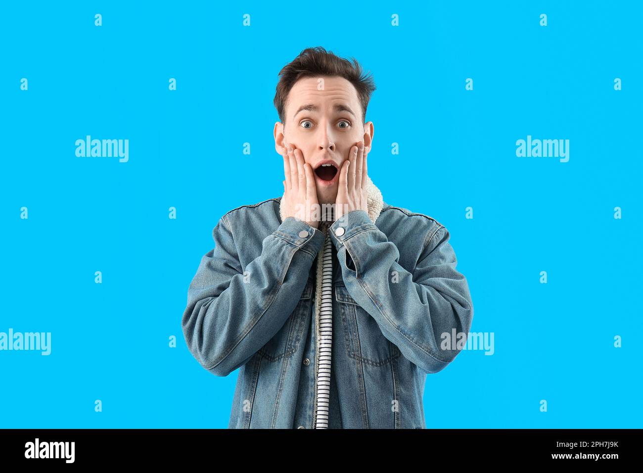 Scared young man on light blue background Stock Photo - Alamy
