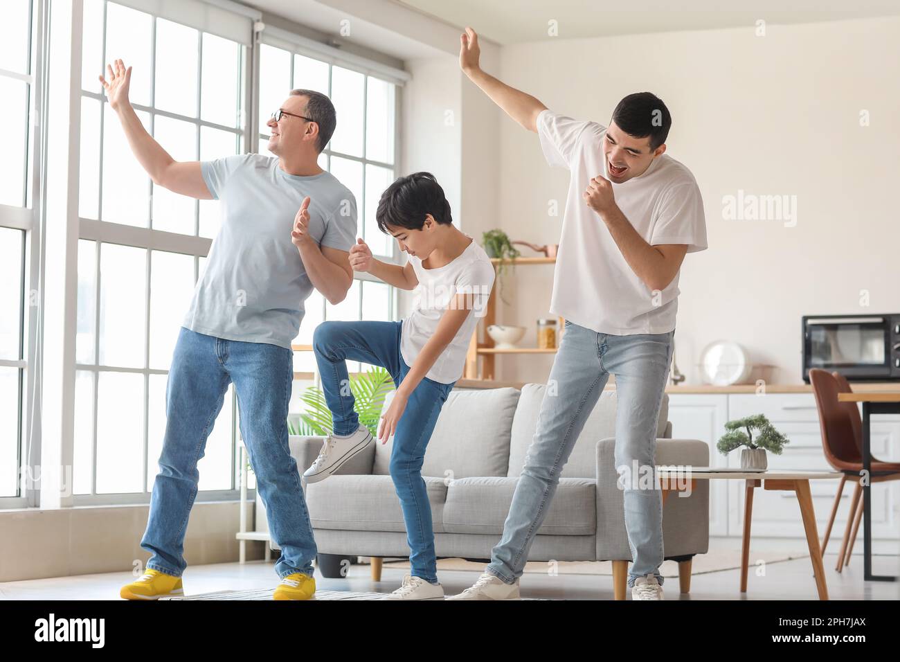 Happy little boy with his dad and grandfather dancing at home Stock ...