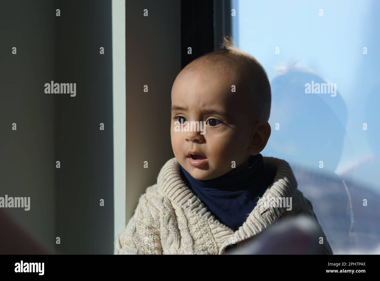 Portrait of a kid with shocked face sitting beside window with copy ...