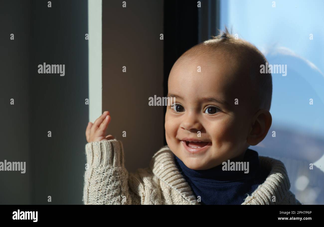 happy cute baby boy sitting beside window in sun Stock Photo - Alamy