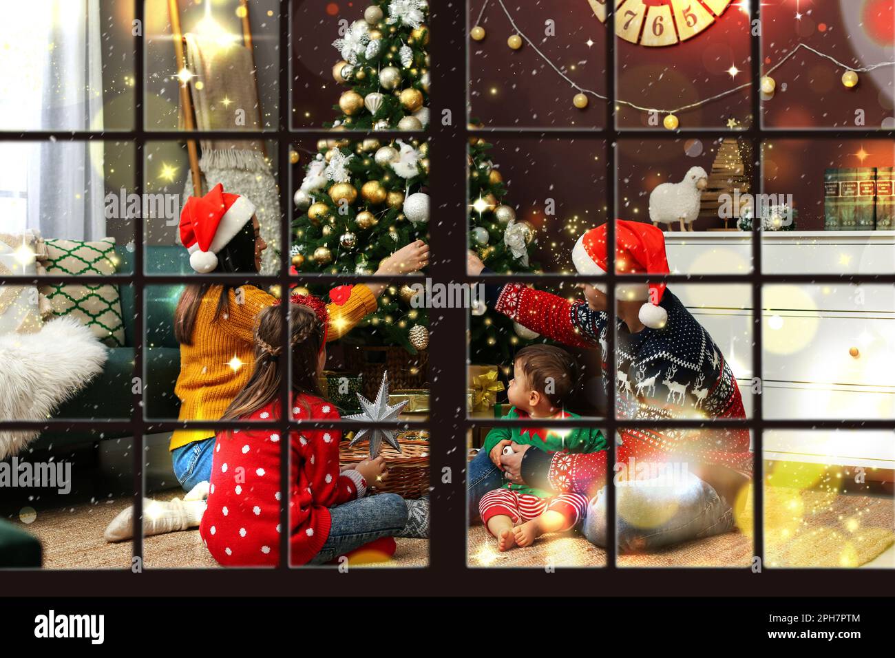 Family decorating beautiful Christmas tree at home, view through window ...