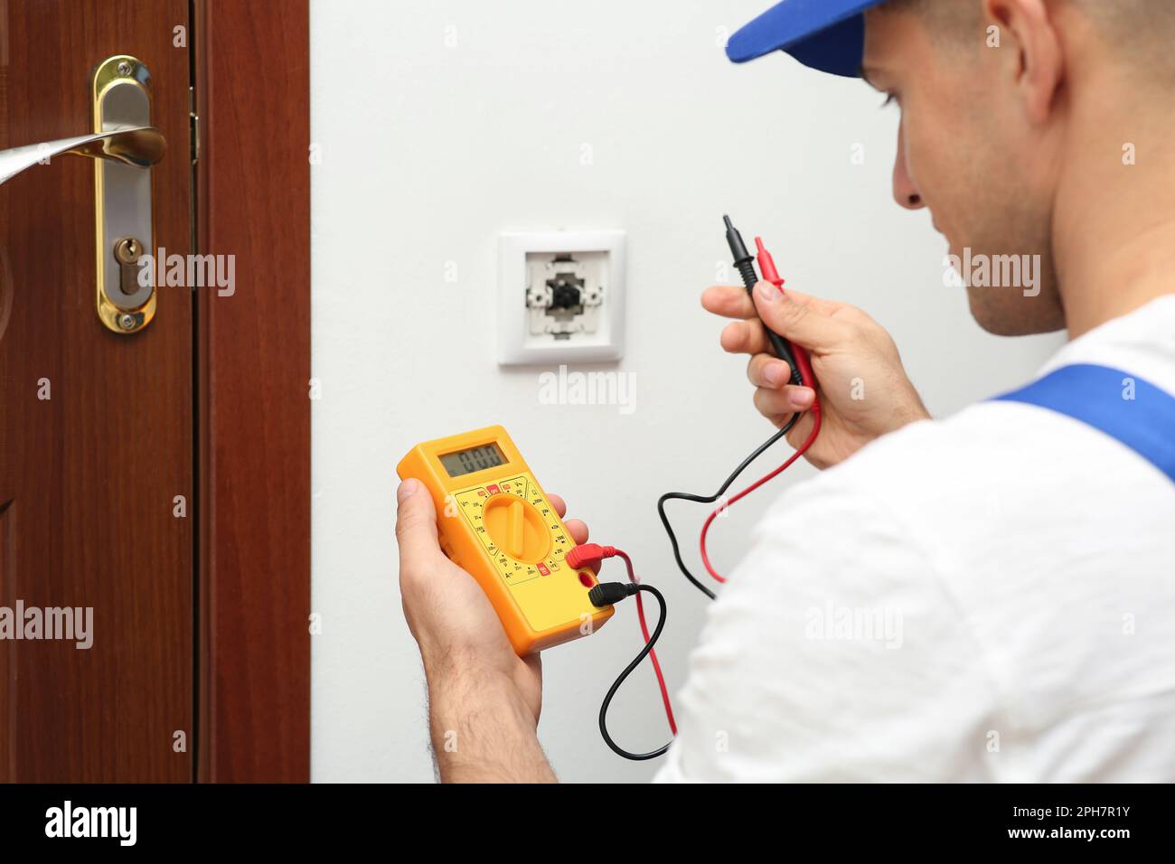 Professional electrician with voltage tester near power light switch ...