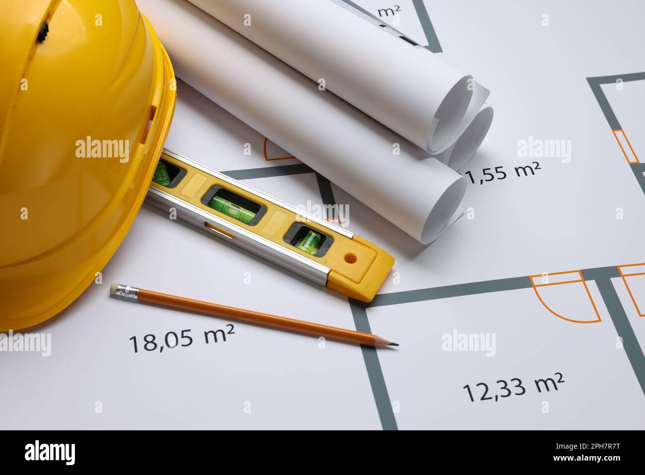 Rolled construction drawings, safety hat, pencil and bubble level on ...