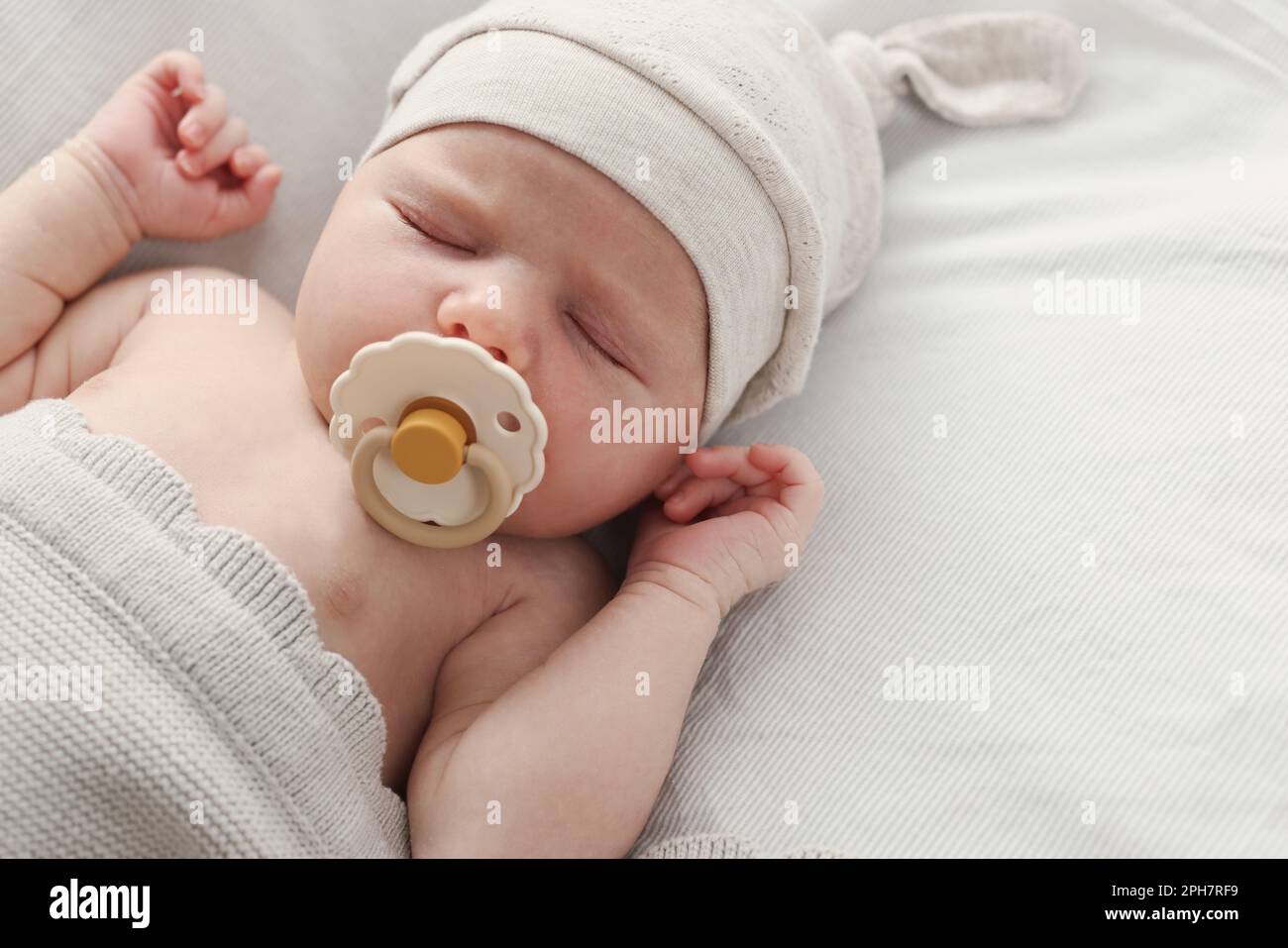 Adorable little baby with pacifier sleeping in bed, top view. Space for ...