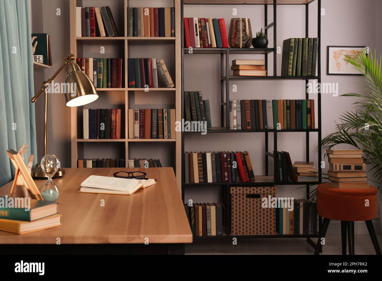 Wooden table and collection of different books on shelves in home ...