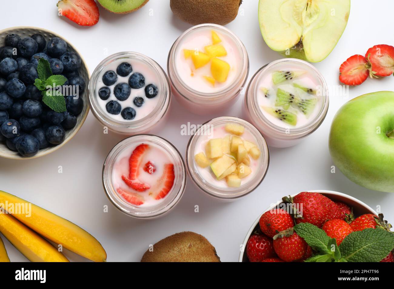 Tasty yogurt in glass jars and ingredients on white background, top ...