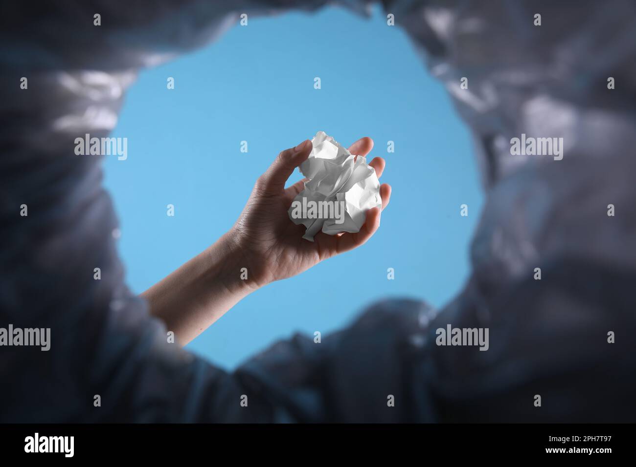 Bottom view of woman throwing crumpled paper into trash bin on light ...