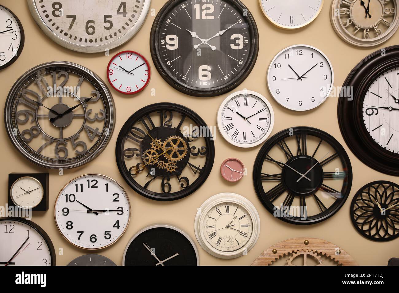 Collection of stylish clocks on beige wall Stock Photo - Alamy
