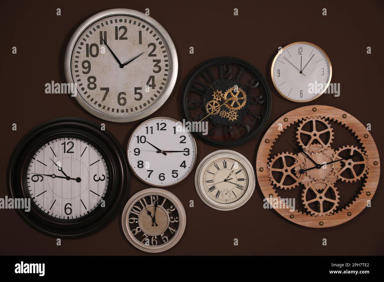 Collection of stylish clocks on brown wall Stock Photo - Alamy