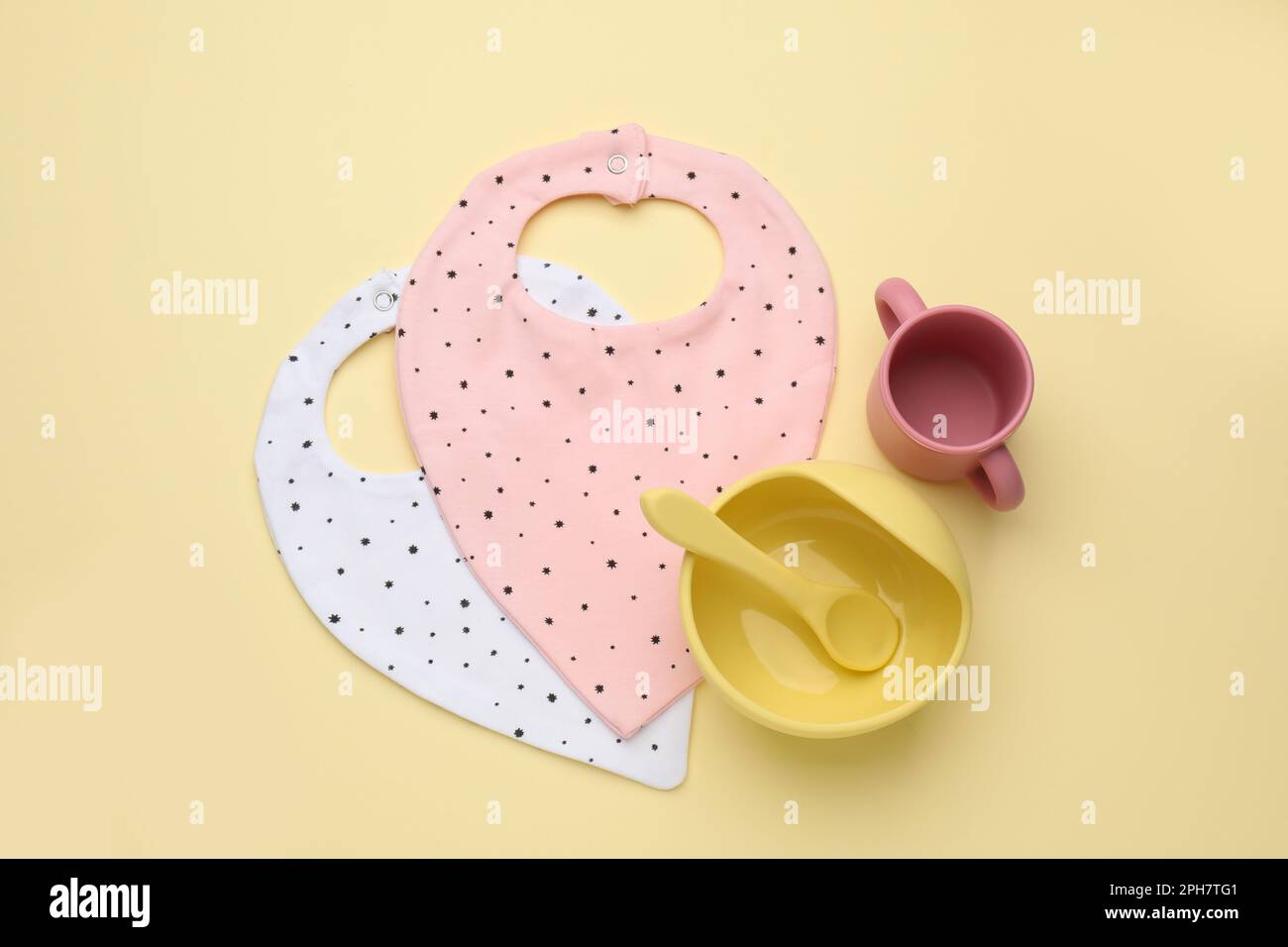 Flat lay composition with baby feeding accessories and bibs on yellow ...