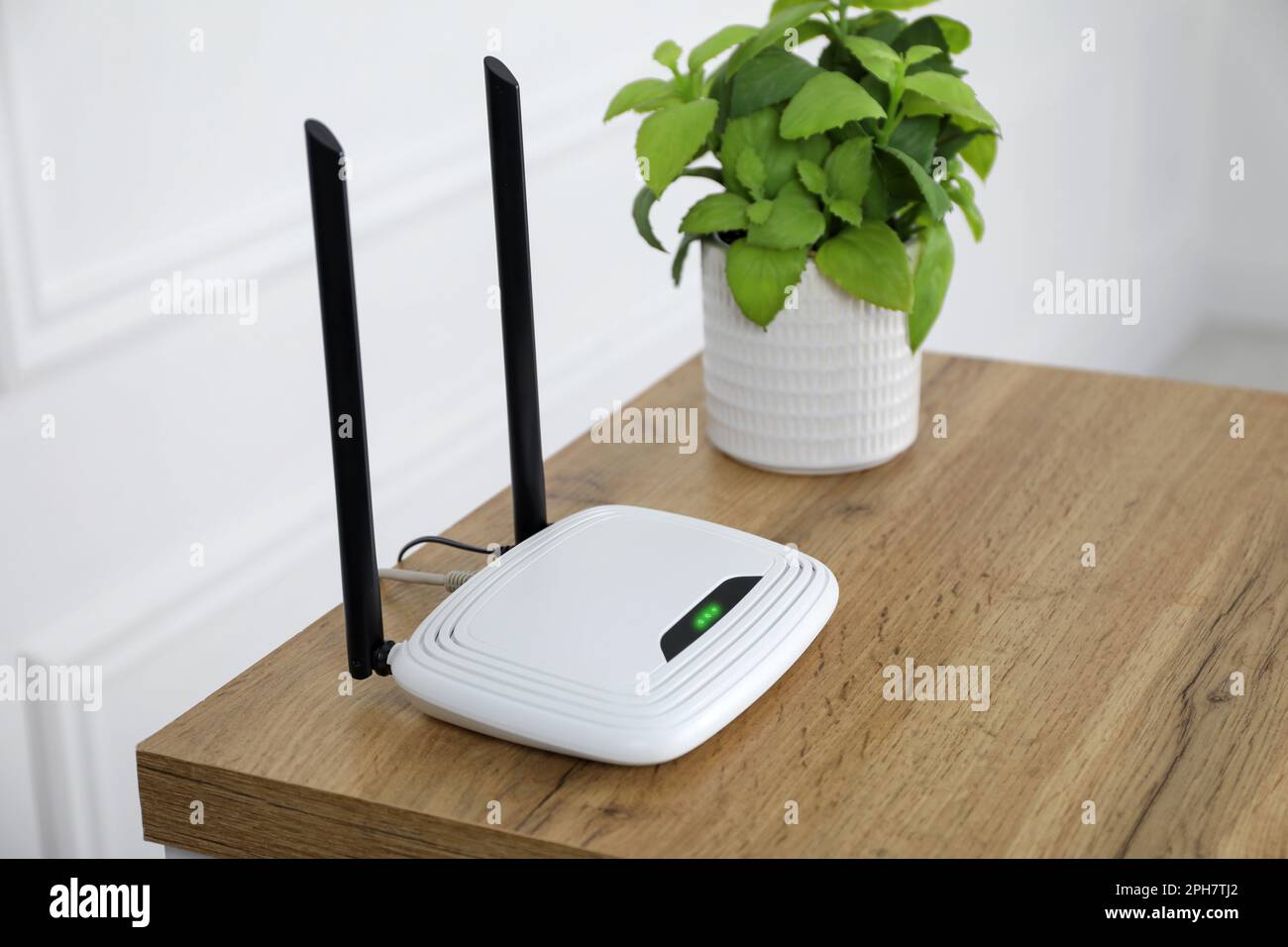 Wi-Fi router and houseplant on wooden table in room Stock Photo - Alamy