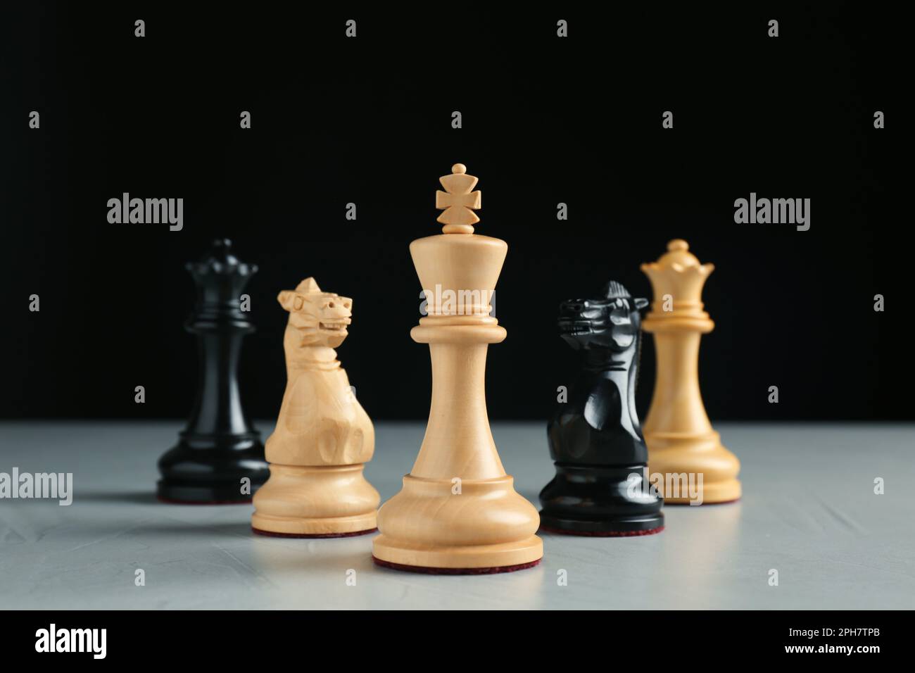 Different chess pieces on grey table against dark background Stock ...