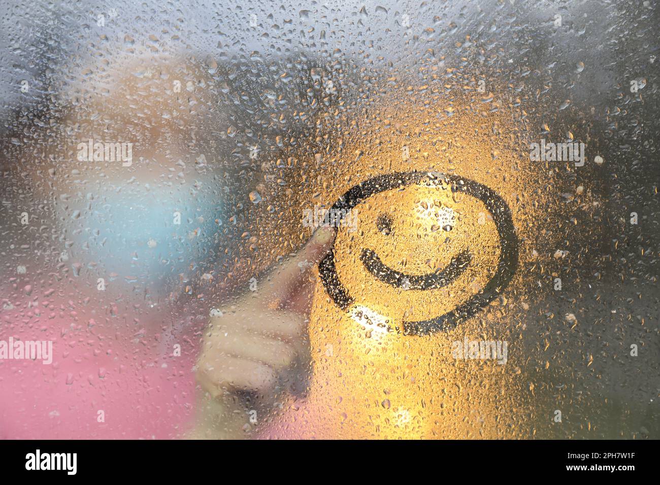 Woman drawing happy face on foggy window at rainy weather, closeup ...