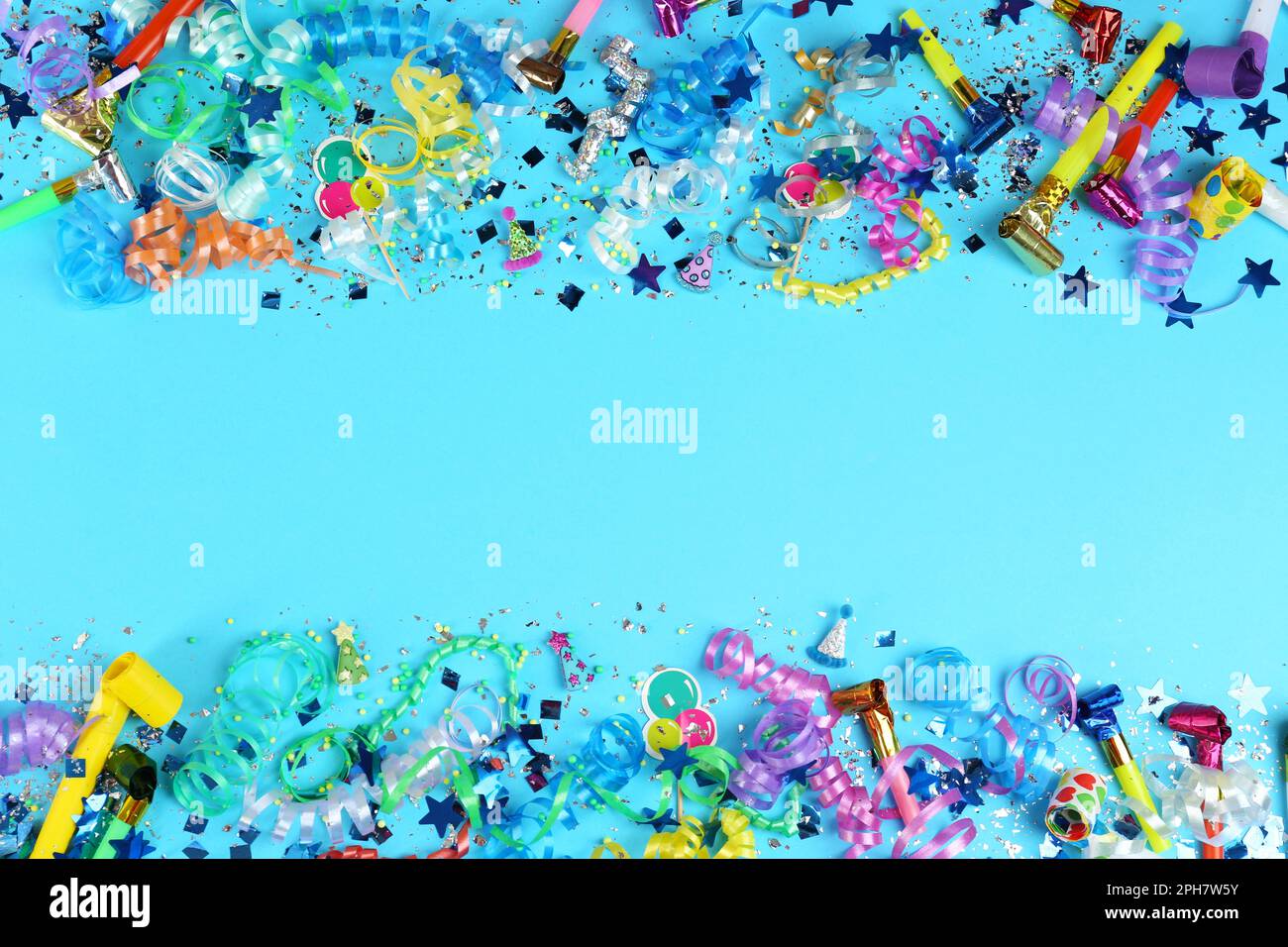 Colorful serpentine streamers, confetti and party horns on light blue ...