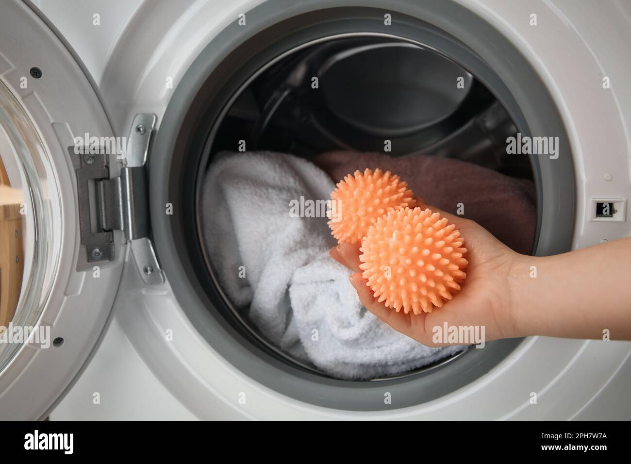 Woman putting dryer balls into washing machine, closeup Stock Photo - Alamy
