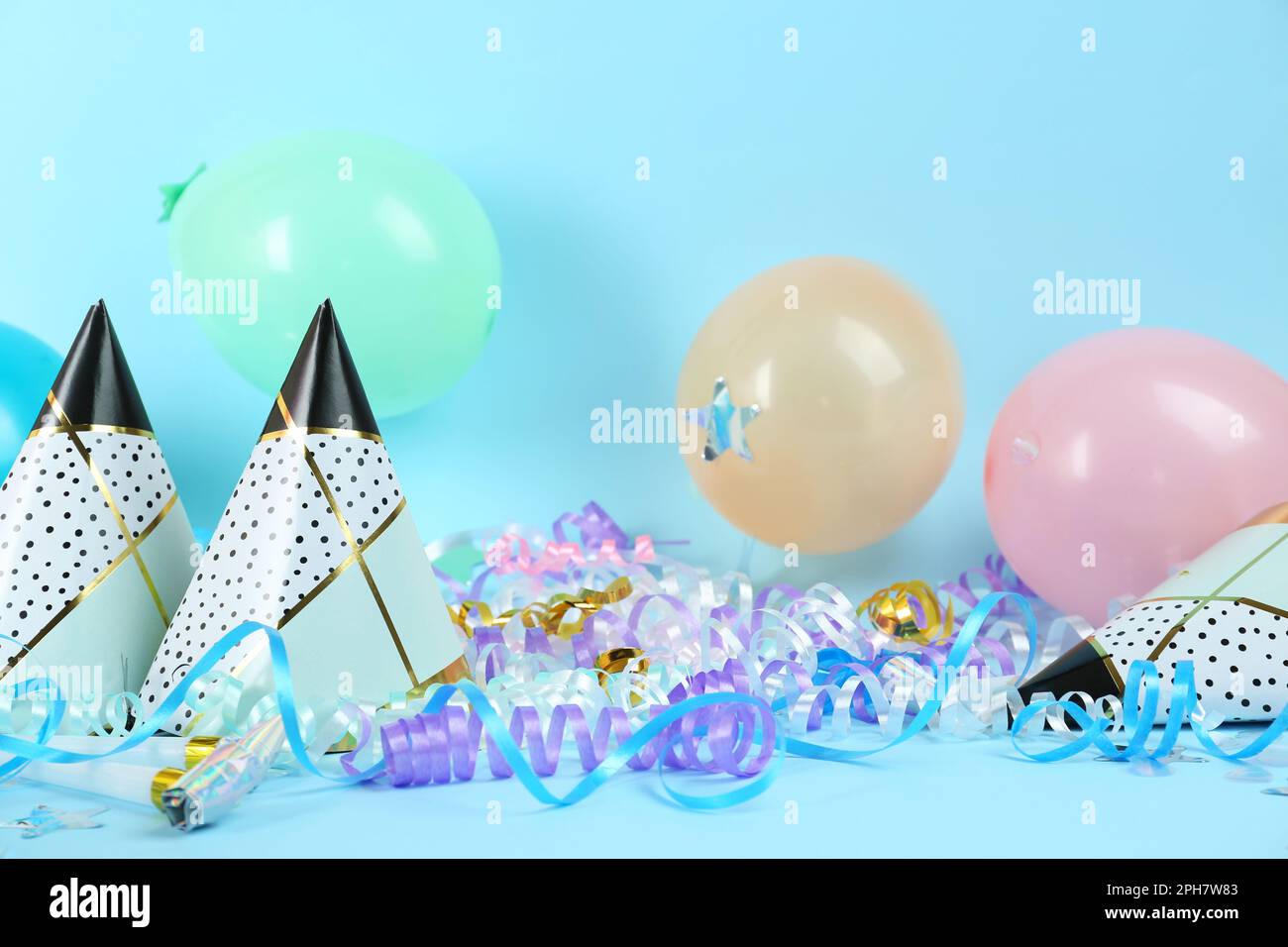 Colorful serpentine streamers, caps, party horns and balloons on light ...