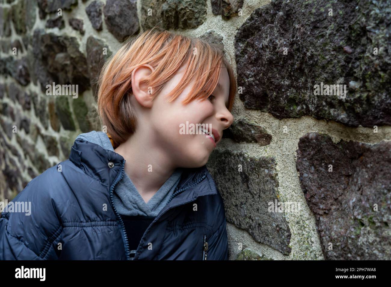 Smiling contented boy near the stone wall. A boy of nine and ten years ...