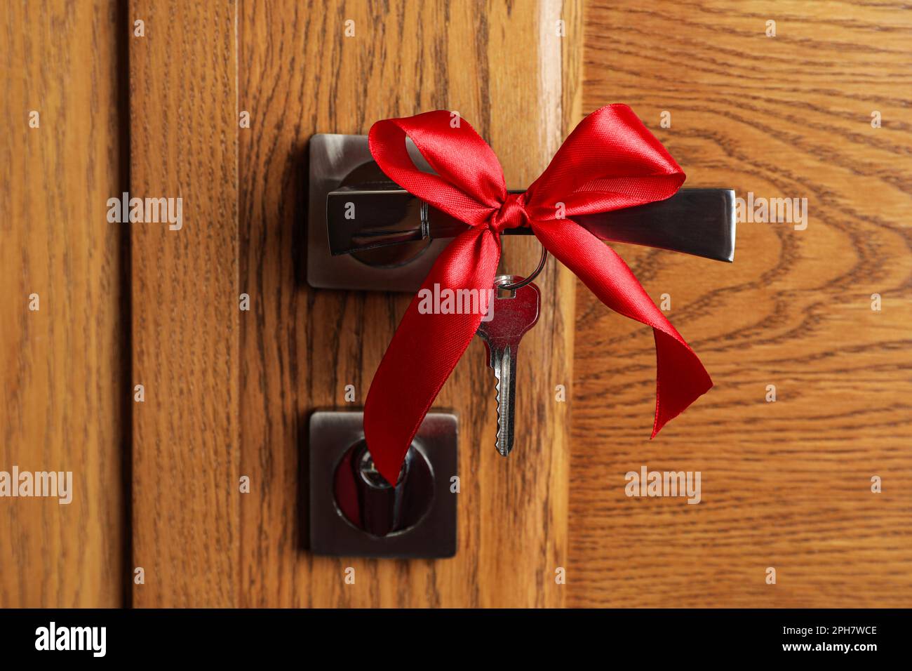 Key with red bow on door handle, closeup view. Housewarming party Stock ...