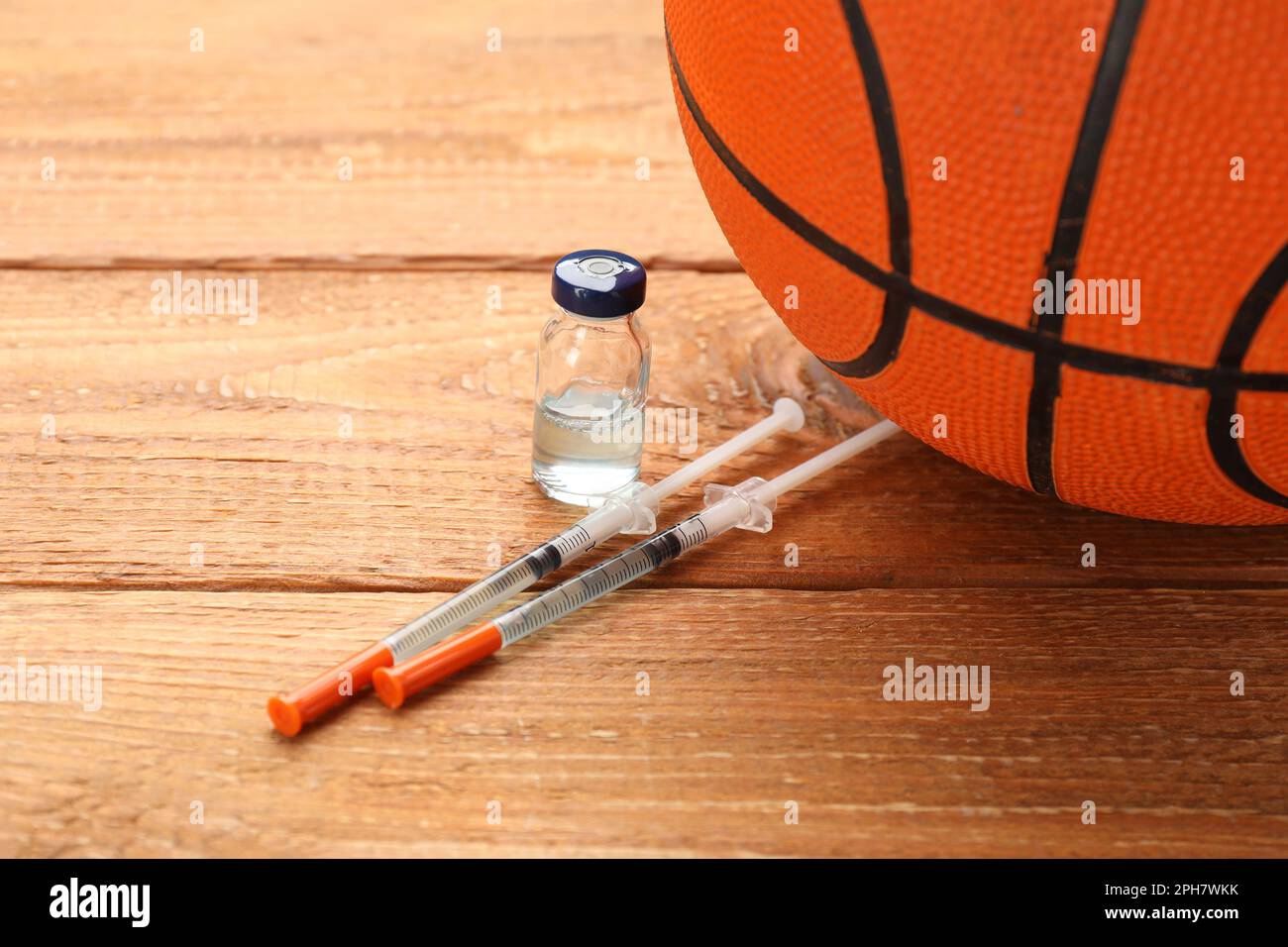 Basketball ball, syringes and vial on wooden table, closeup. Doping ...