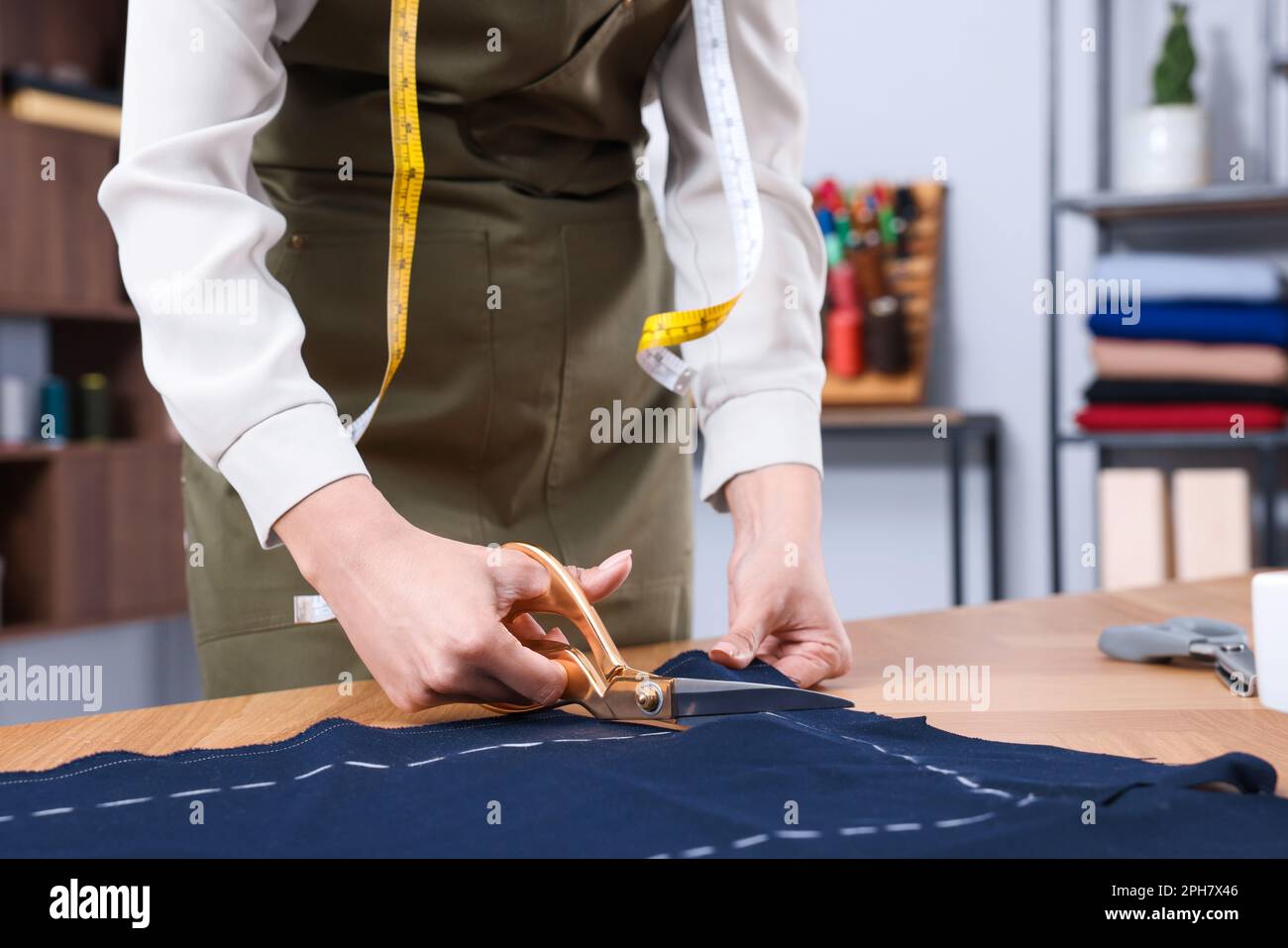 Dressmaker cutting fabric by following chalked sewing pattern in ...