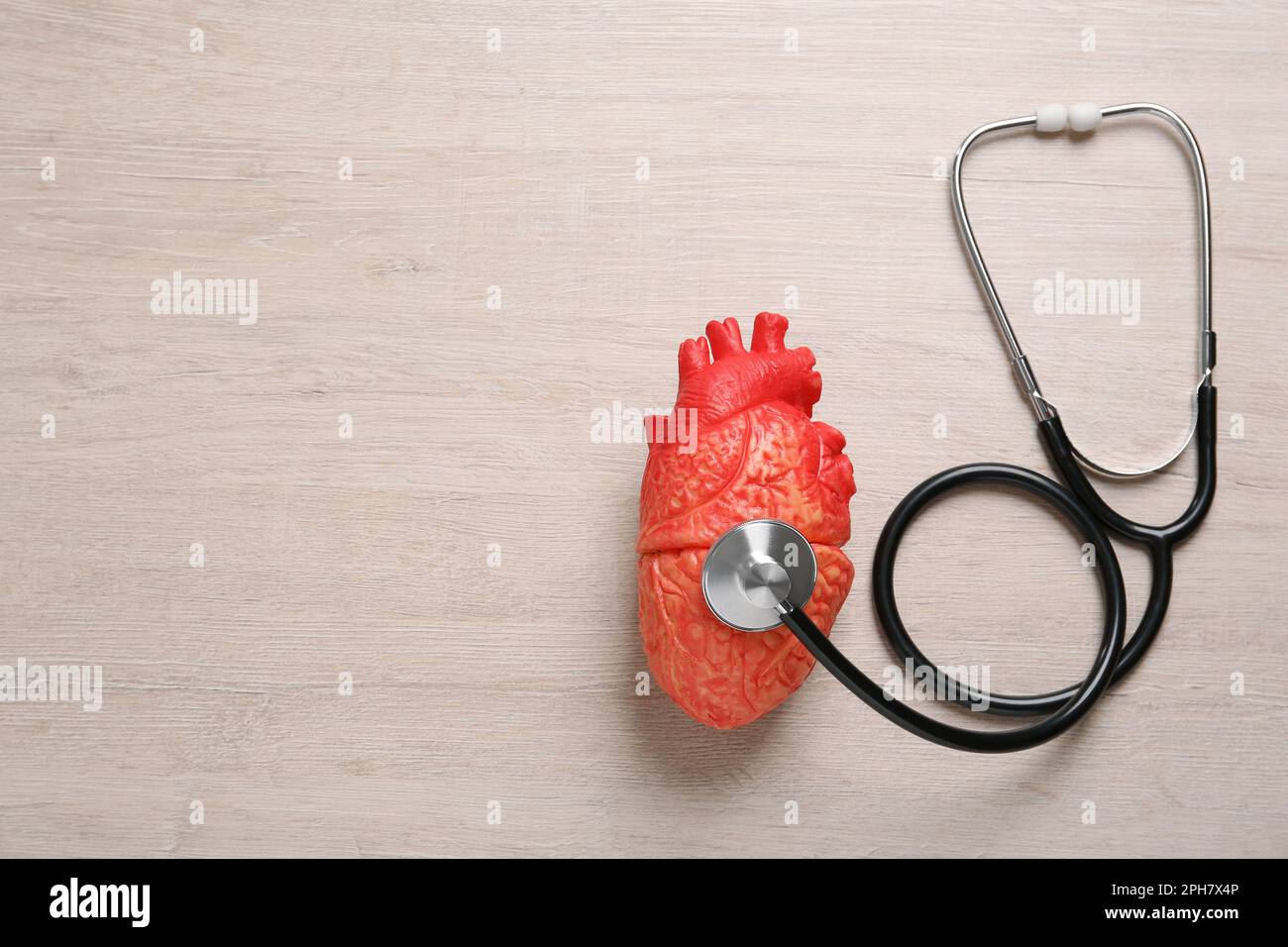 Stethoscope, heart model and space for text on wooden background, flat ...