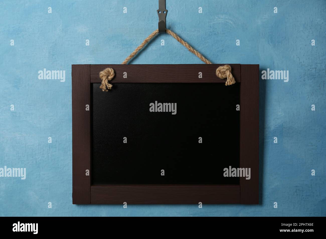 Clean small black chalkboard hanging on light blue wall Stock Photo - Alamy