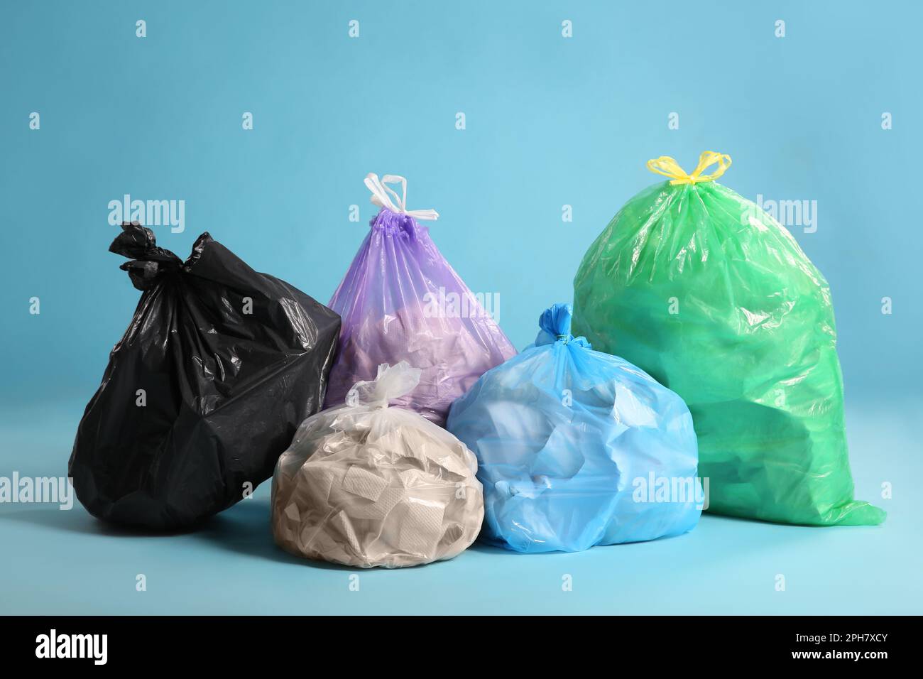 Different trash bags full of garbage on light blue background Stock ...