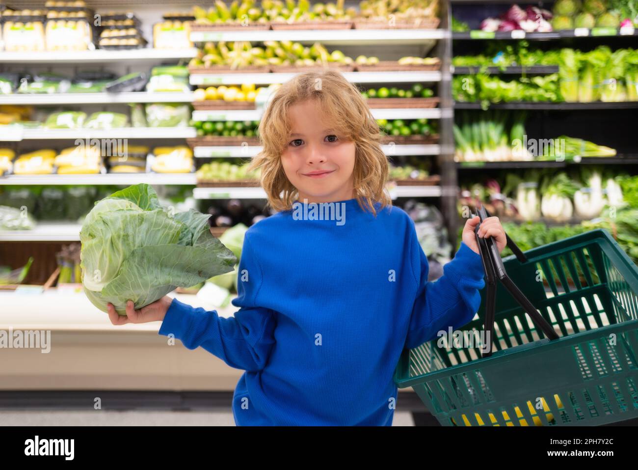 Child with cabbage. Kid is choosing fresh vegetables and fruits in the ...
