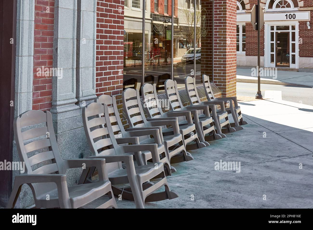 A group of resin rocking chairs are seen lined up against the brick ...