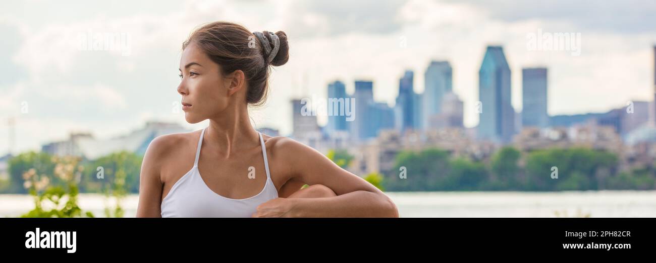 Asian woman doing yoga stretch for back outside in city park skyline ...