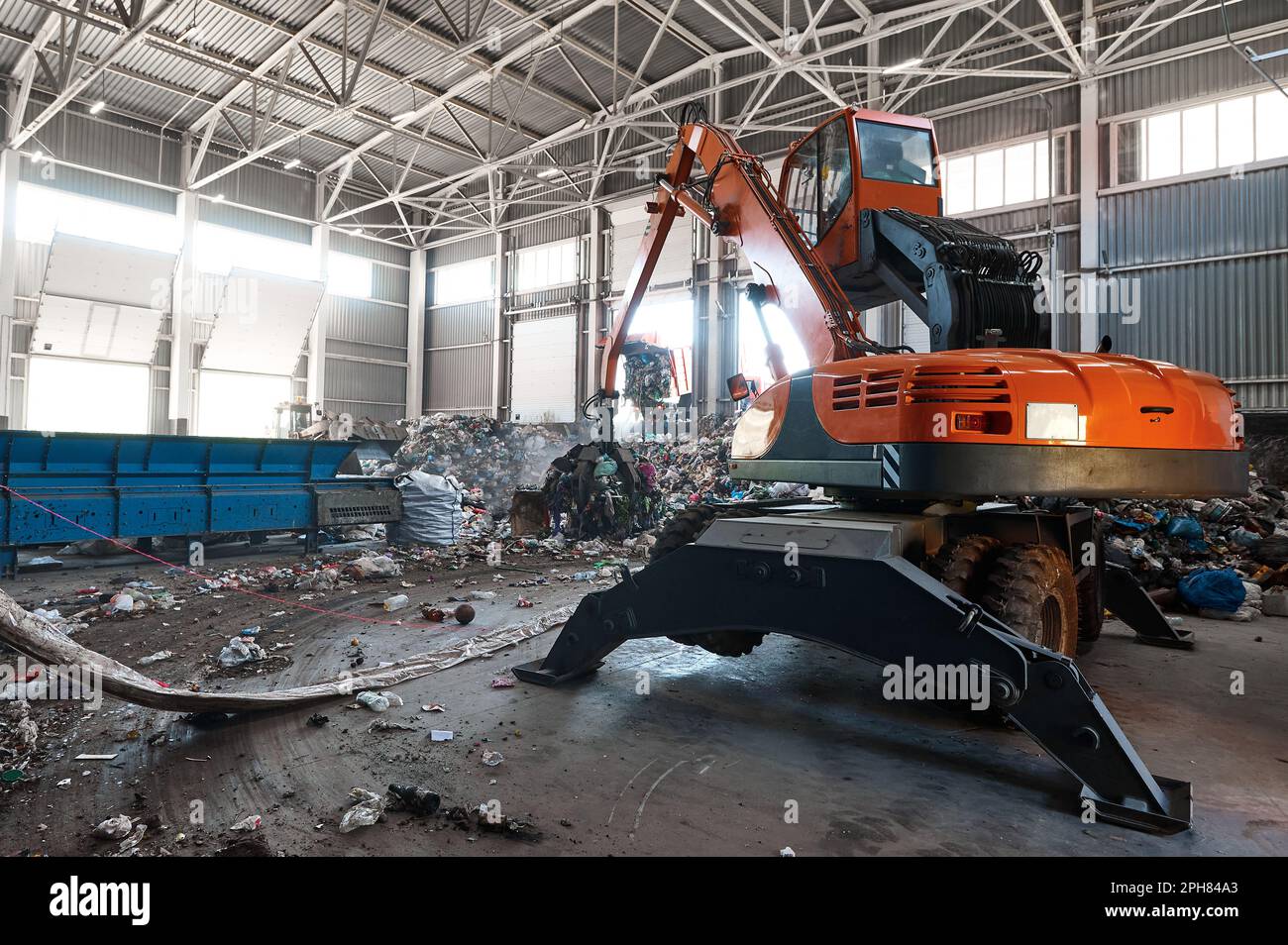 Excavator grabs trash in warehouse of waste processing plant Stock ...