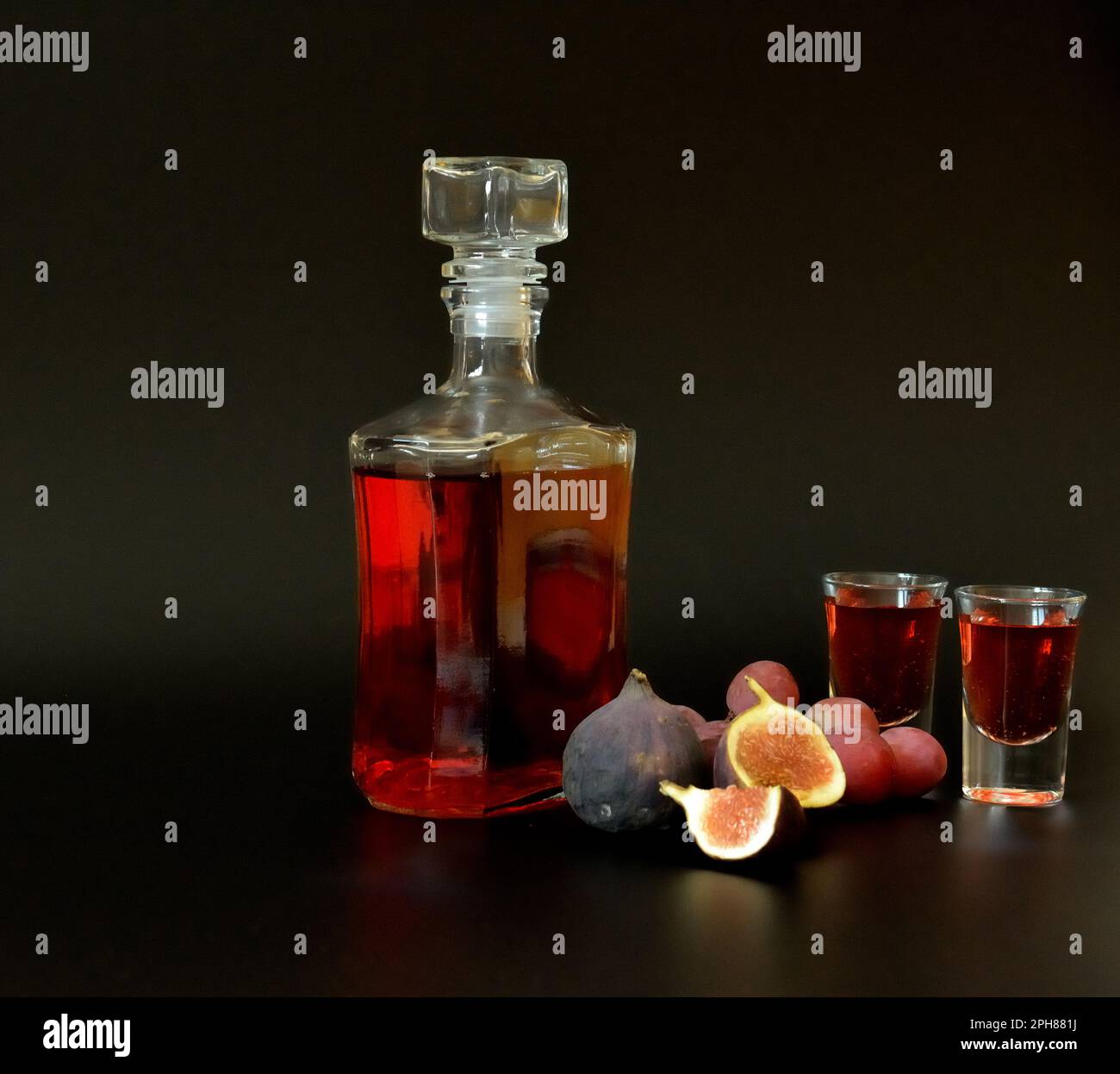 Homemade fruit liqueur in a bottle and two glasses on a black ...