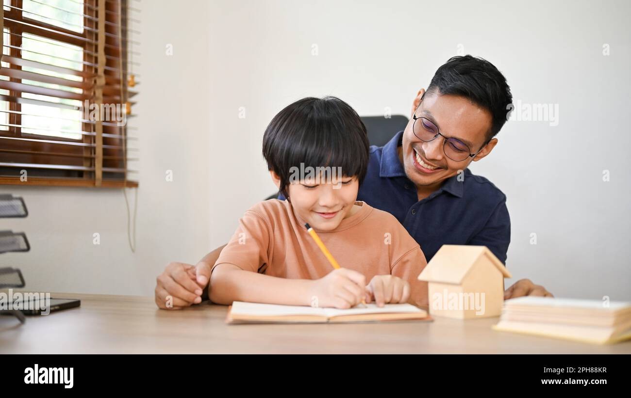 A caring and happy Asian father teaching his son to write the alphabet ...