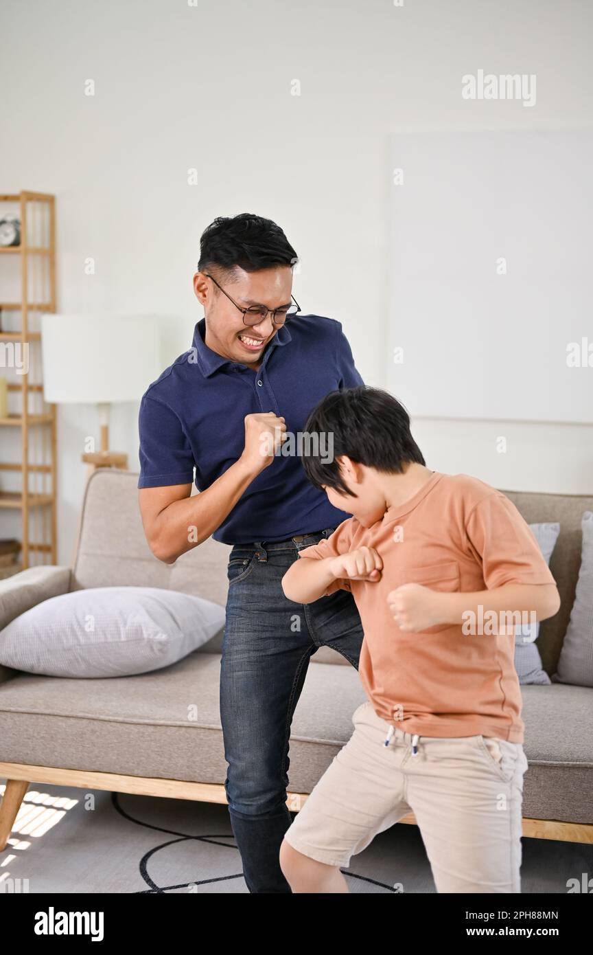 Cheerful and playful Asian dad and little son enjoying dancing in the ...