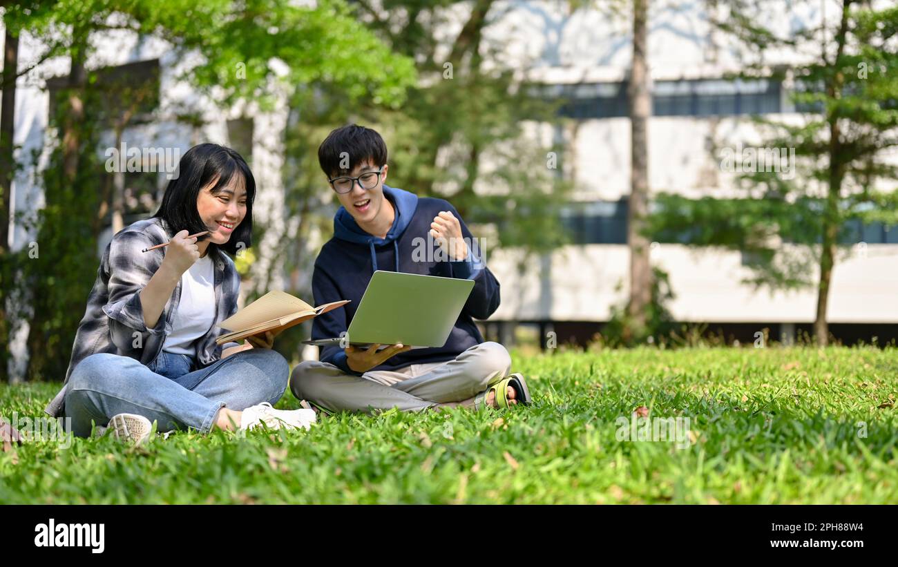 Two cheerful young Asian college students are rejoicing and celebrating ...