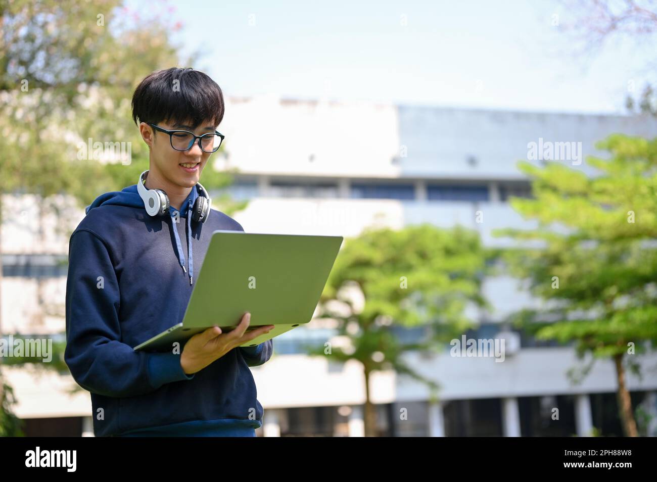 Smart and happy young Asian male college student using his portable ...