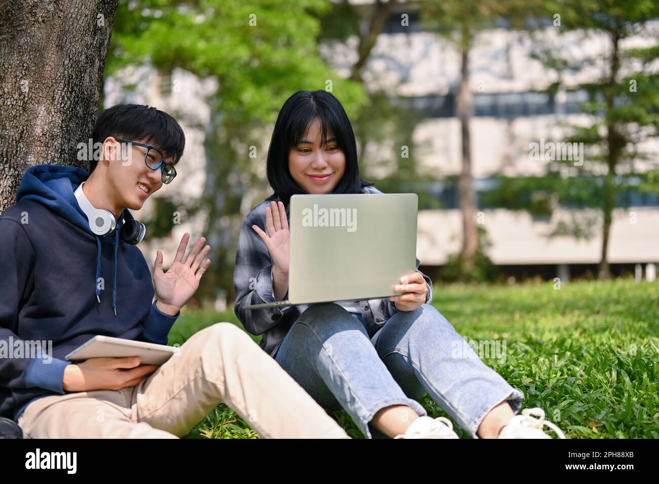 Two smiling and happy young Asian college students are having an online ...