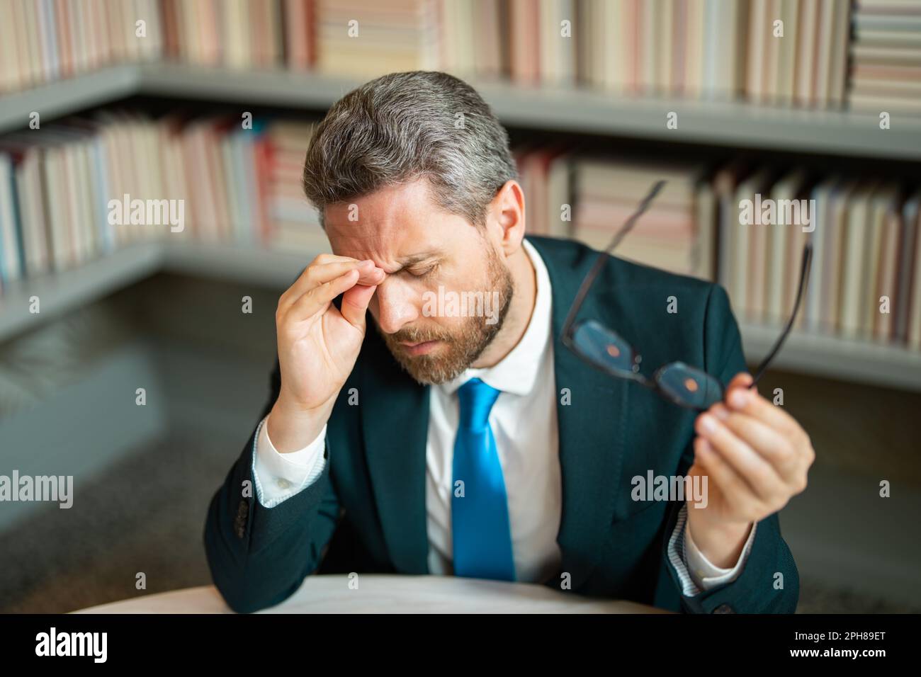 Headache, tiredness and stress. Man in suit uses a laptop, is tired got ...