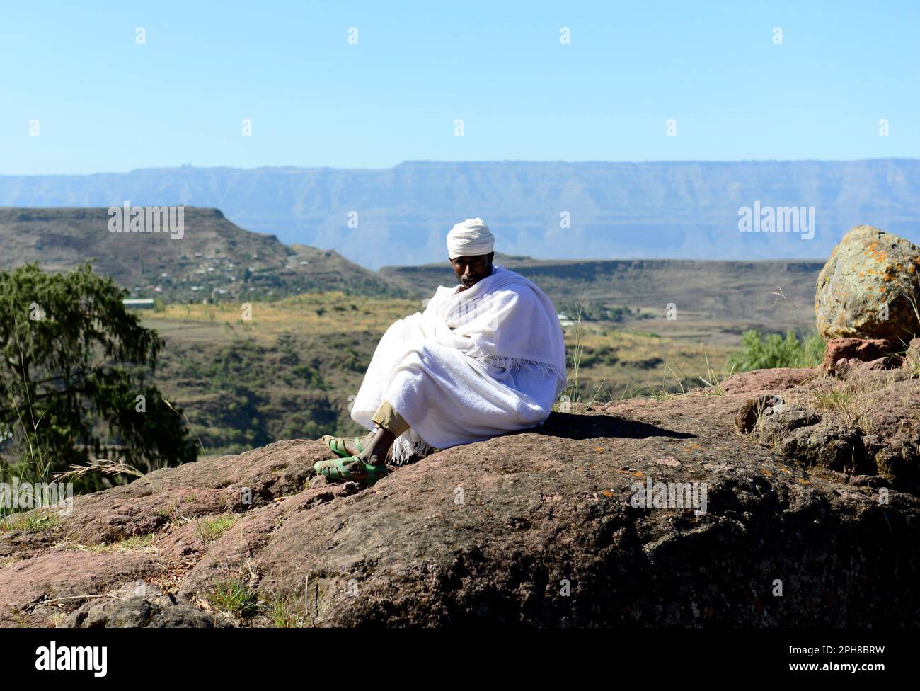 An Ethiopian Orthodox priest sitting above a Rock-hewn church in ...