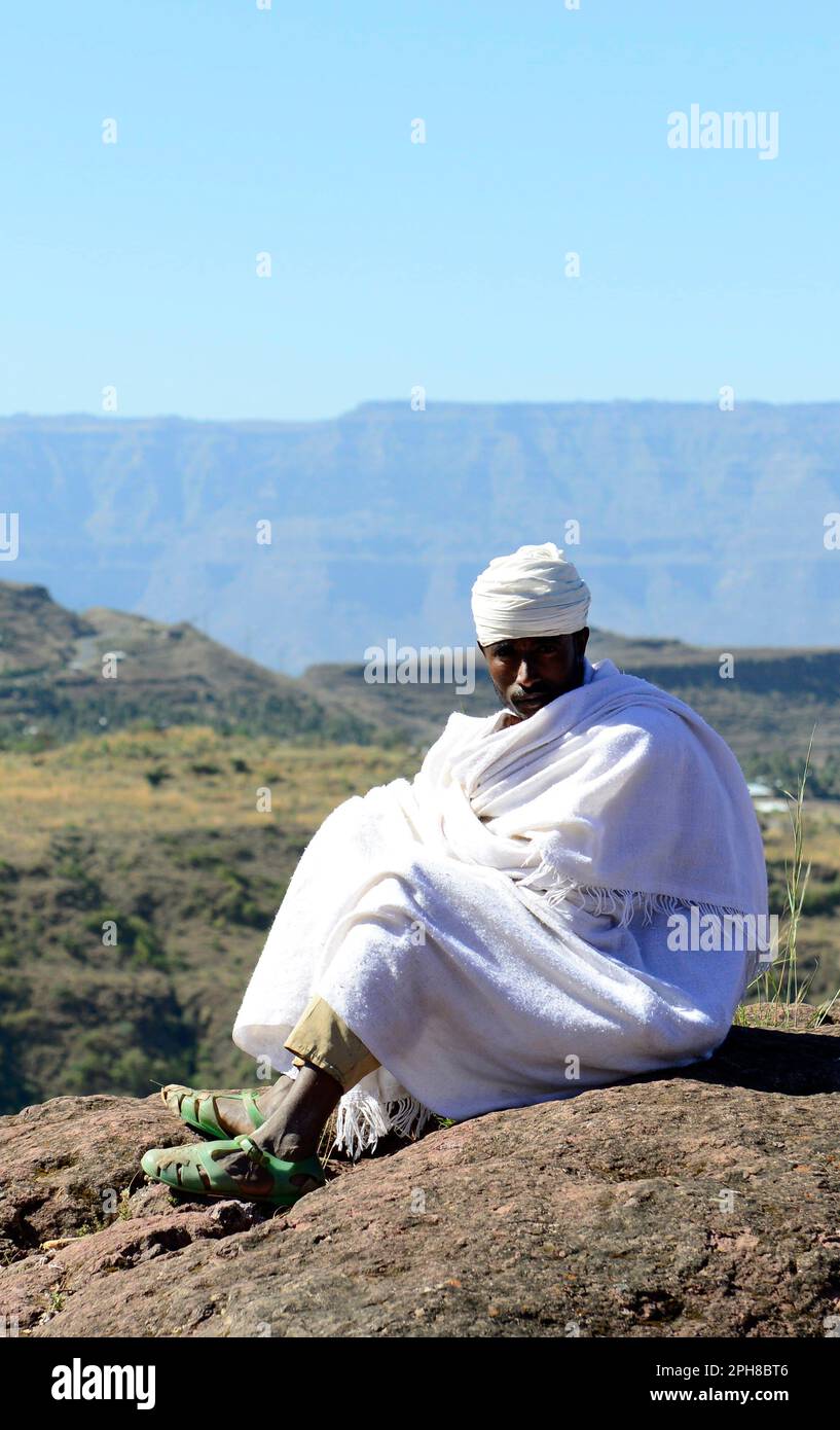 An Ethiopian Orthodox priest sitting above a Rock-hewn church in ...