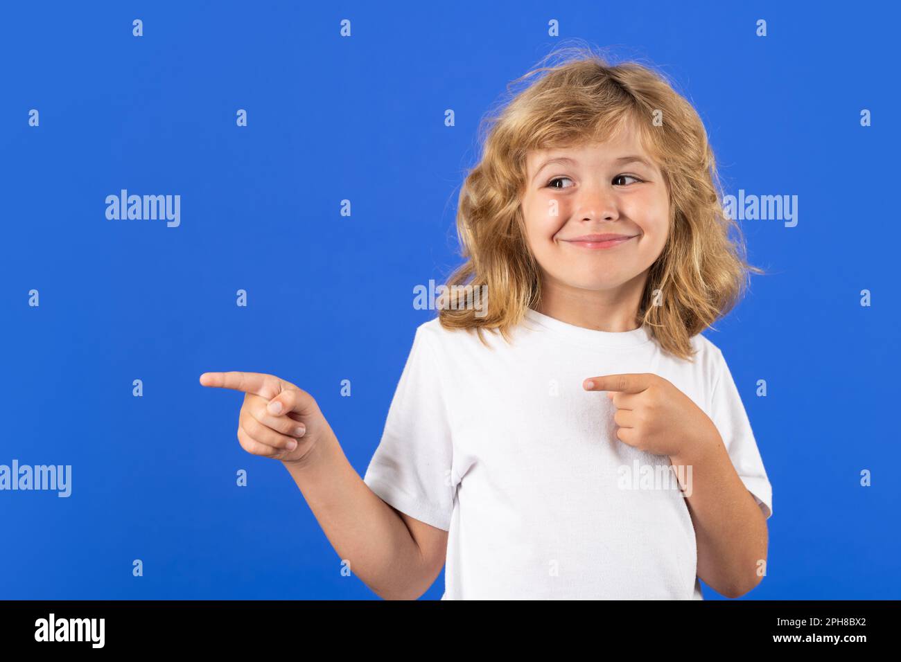 Child boy pointing away on blue isolated studio background. Portrait of ...