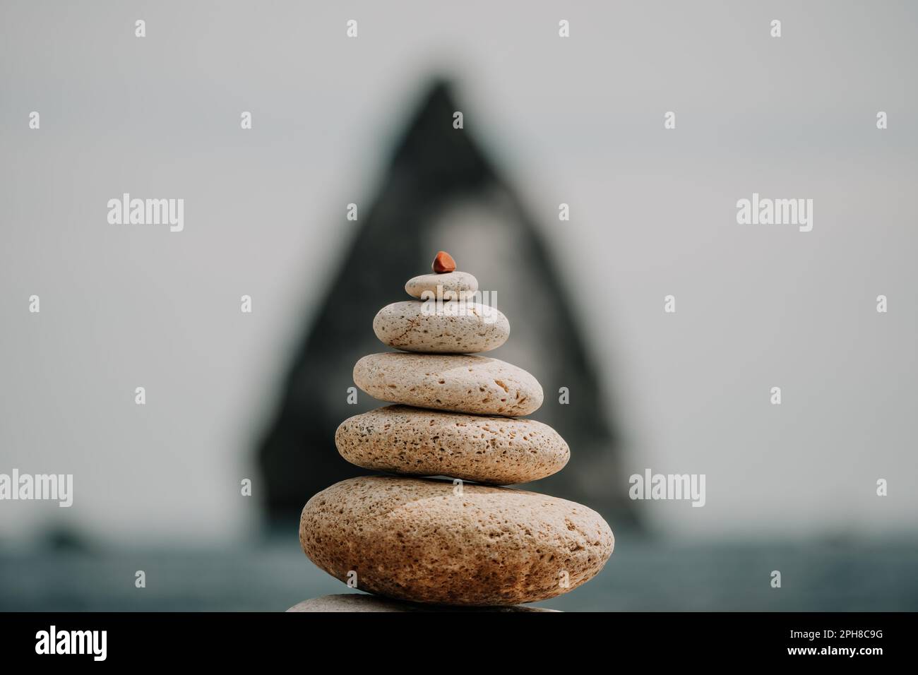 balanced rock pyramid stands tall on sea pebble beach. Selective focus ...