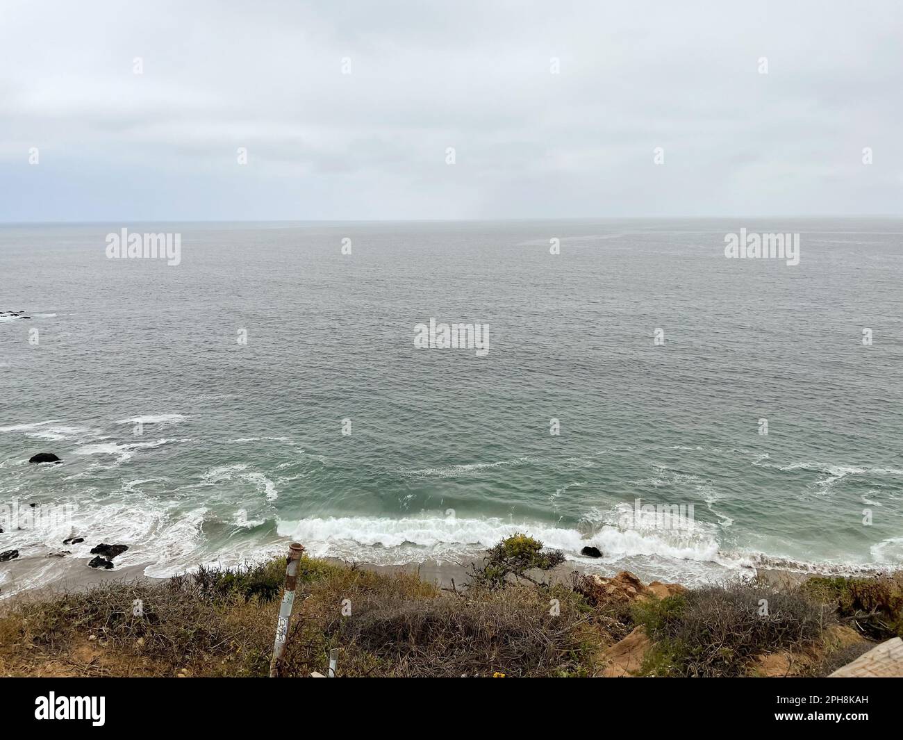 A scenic coastal landscape featuring a rocky cliff and lush vegetation ...