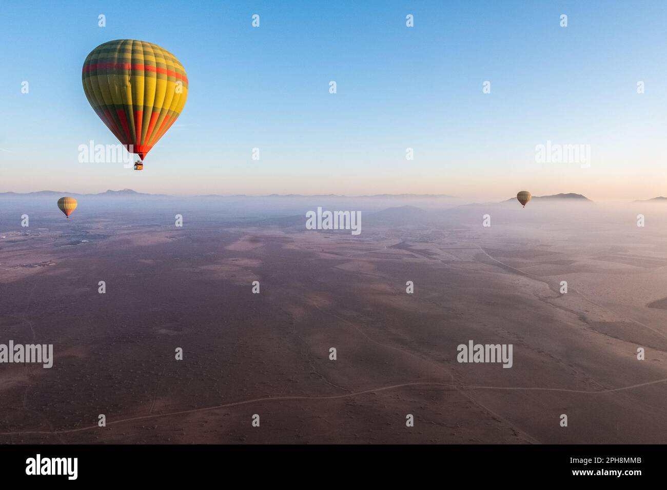 Colorful hot air balloons floating above the vast Moroccan desert ...