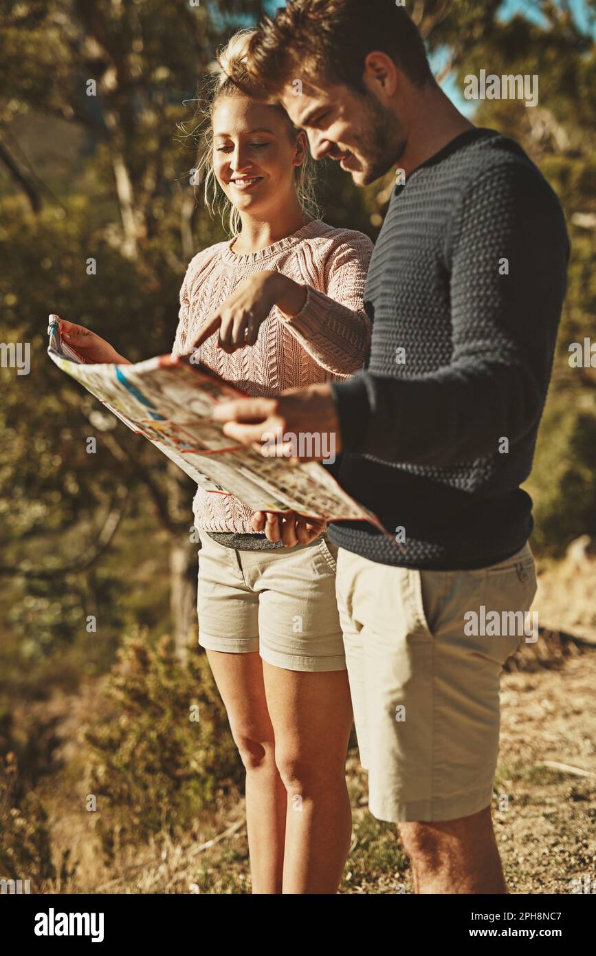 Where will we go next. a young couple looking at a map while out hiking ...