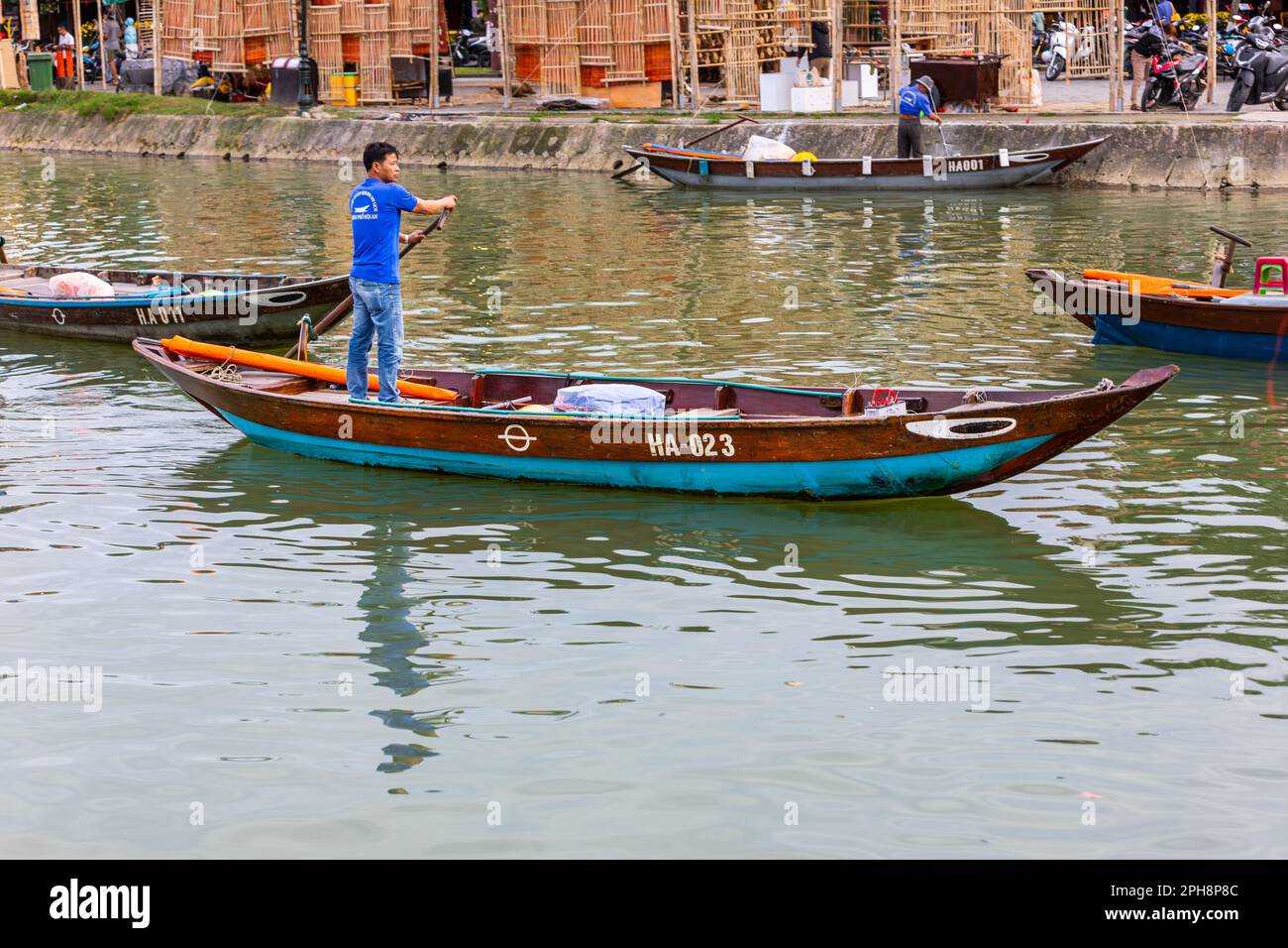 A young Vietnamese young man rowing a small boat on Thu Bon River in ...
