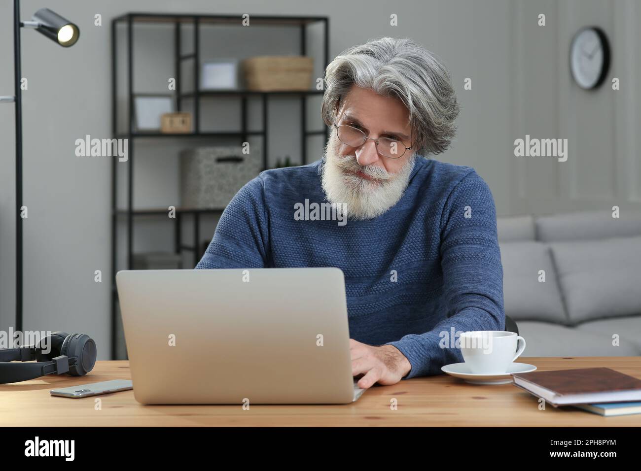 Middle aged man with laptop learning at table indoors Stock Photo - Alamy
