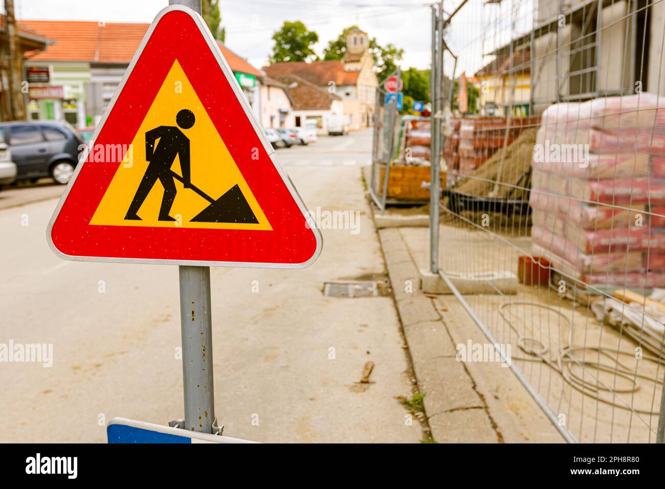 Red triangle traffic sign for road works and blue signpost for indicate ...
